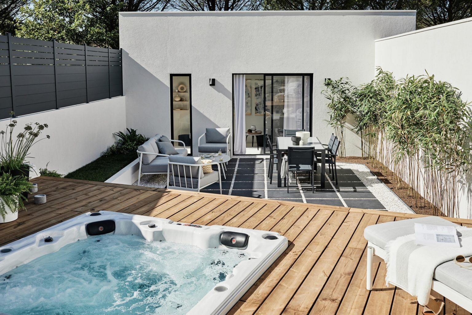 Un spa intégré dans une terrasse en bois pour un petit jardin minéral