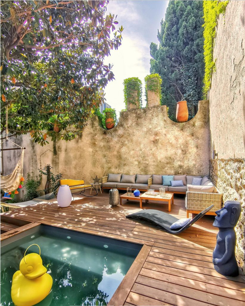 Une mini piscine intégrée dans une terrasse bois pour un jardin de ville